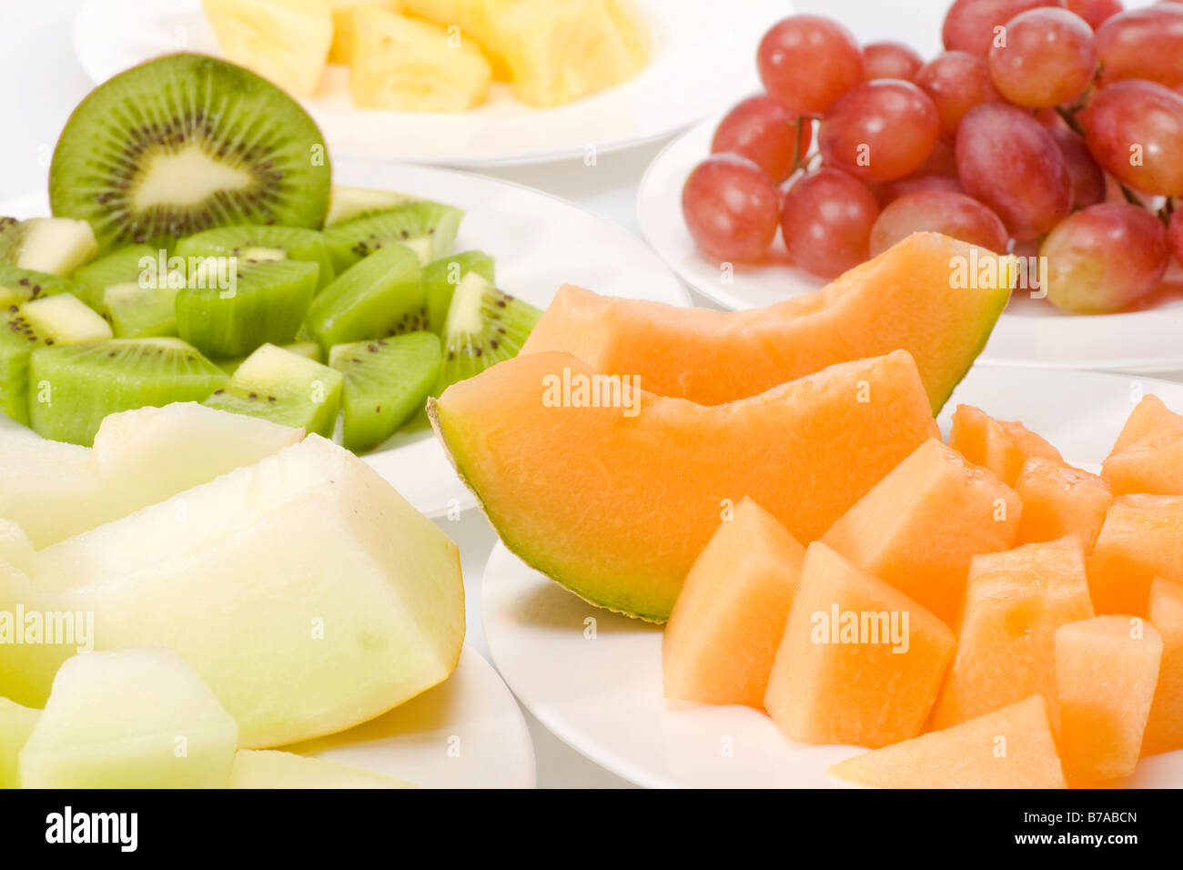 Sliced exotic fruit on plates, sugar melon, honeydew melon, pineapple ...