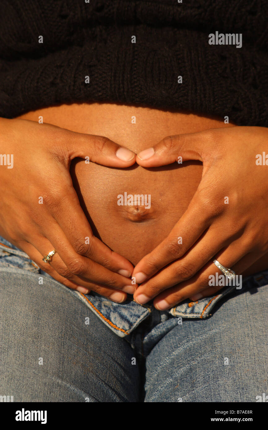 Pregnant lady in black sweater shapes belly heart with hands Stock ...