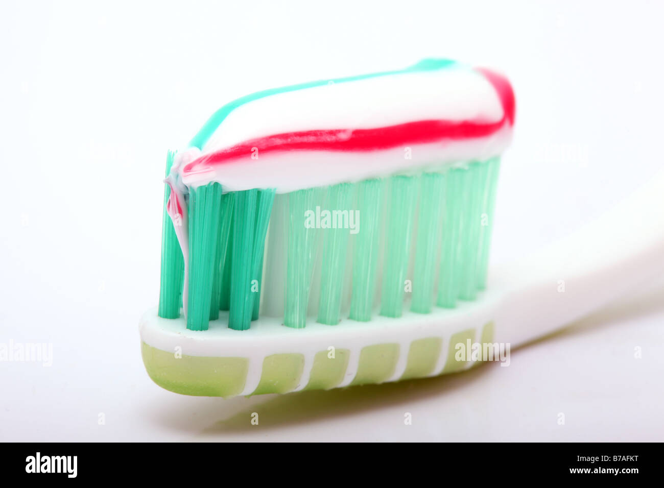 toothpaste on green toothbrush closeup on white background Stock Photo ...
