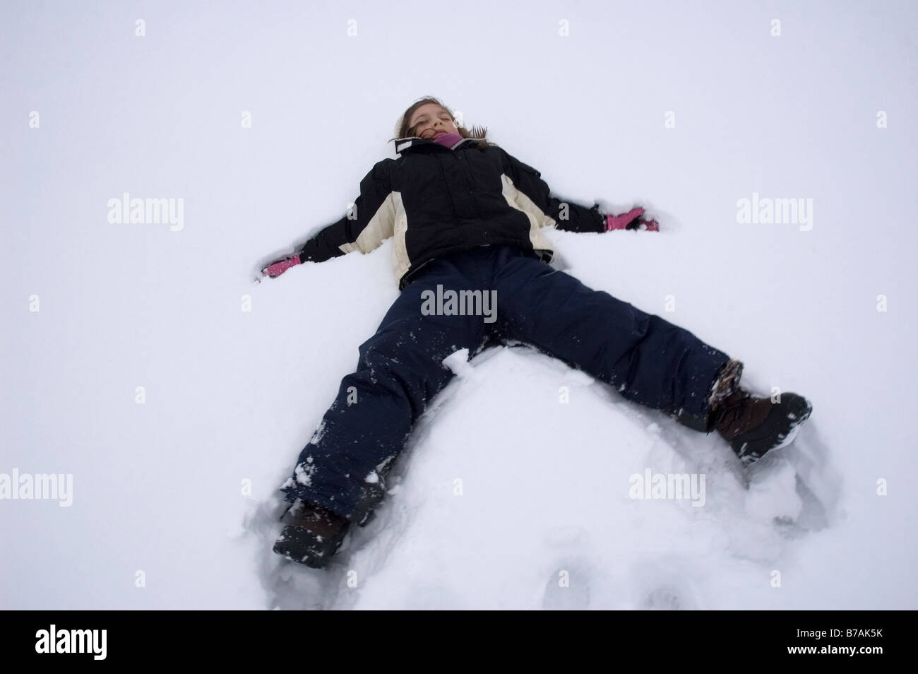 Girl making snow angel Stock Photo - Alamy