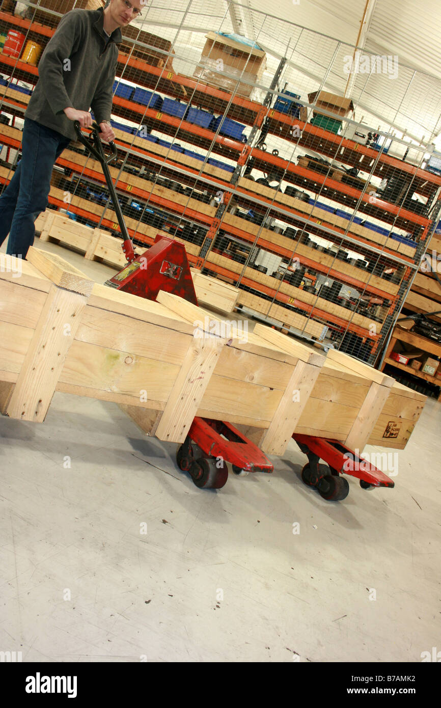 Man moving a wooden crate with a pallet truck in a UK warehouse Stock ...