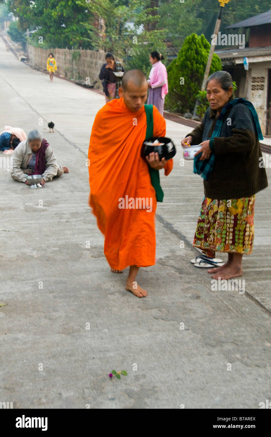 monks receving alms at dawn in the Mon community of Sangklaburi ...