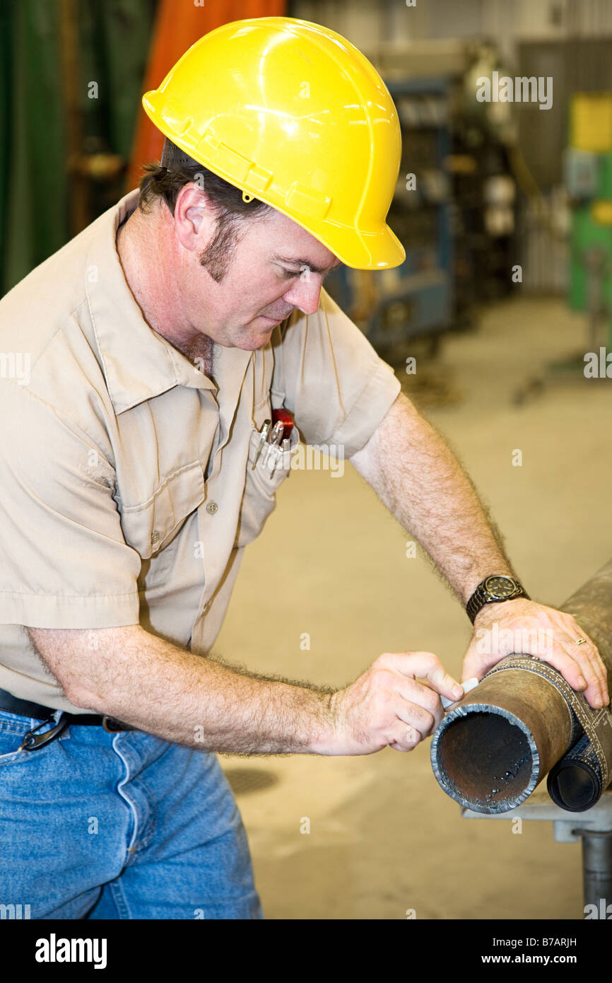 Construction worker marking where he wants to cut a pipe Authentic and ...