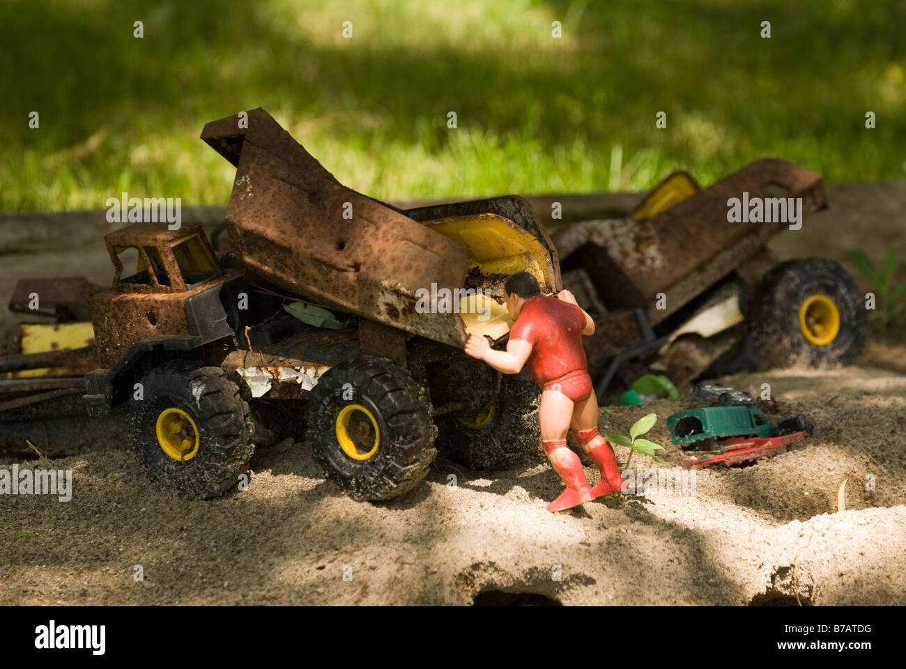 action man toy pushing rusty toy in sand pit Stock Photo - Alamy