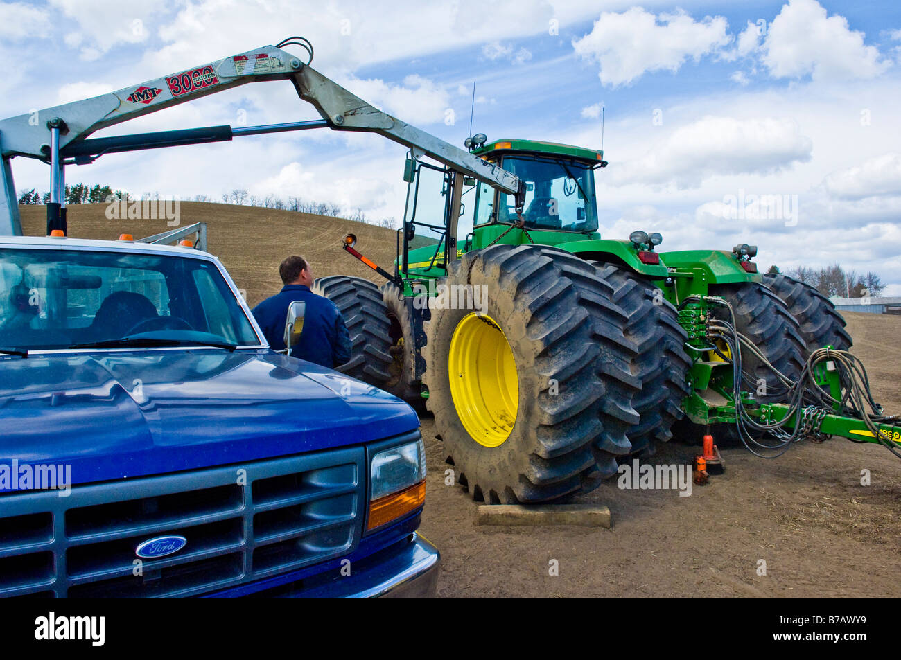 A tire technician changes a tractor tire in the field during spring ...