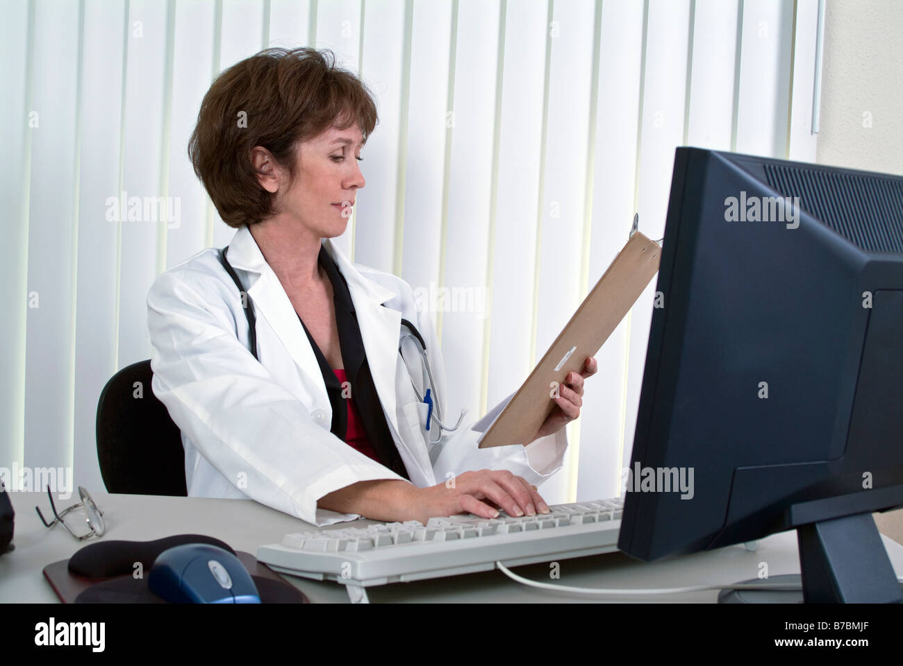A woman dressed as a doctor entering information from a report into a ...