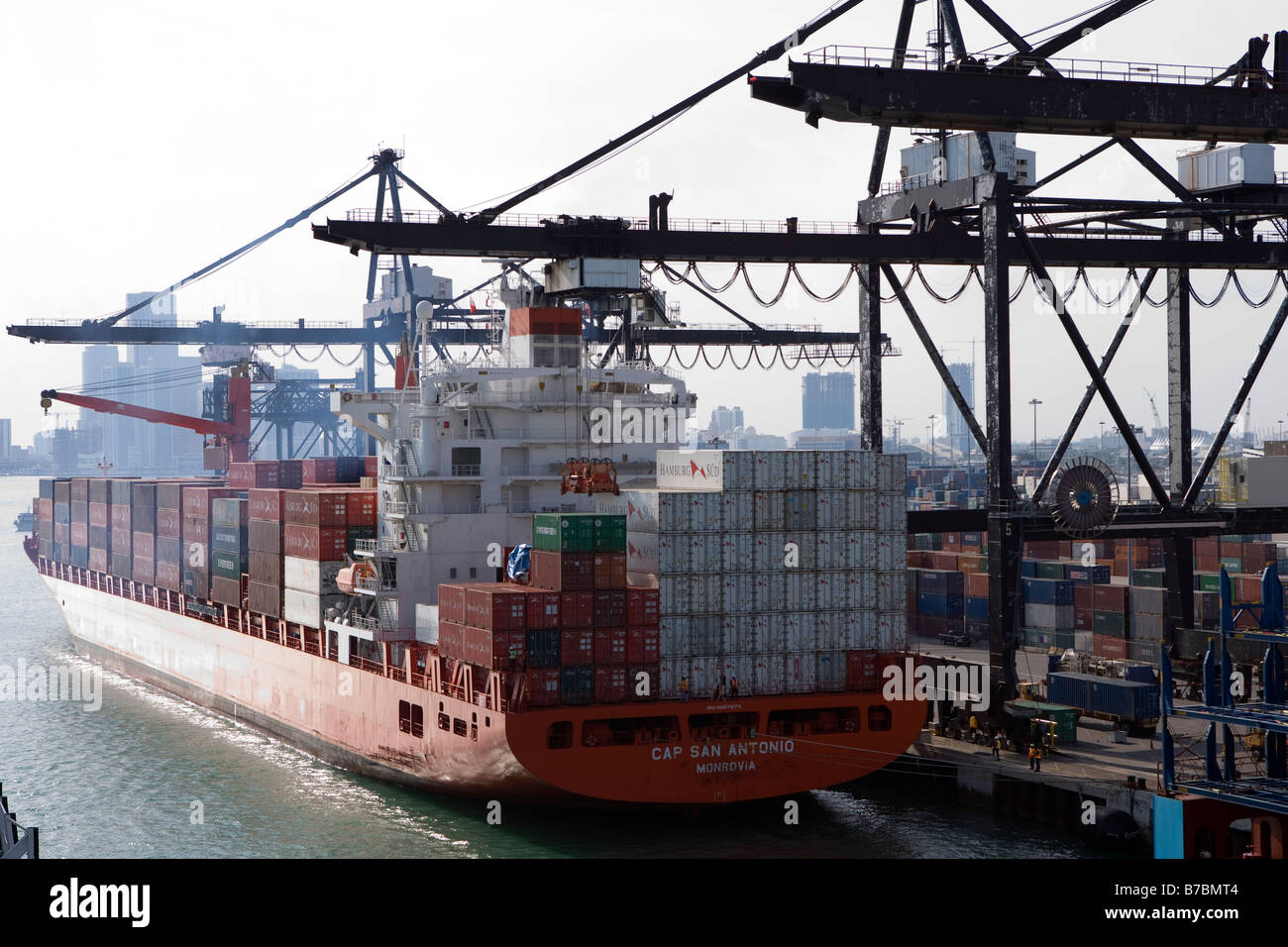 Dockers and gantry cranes unload a container ship as it docks in the ...