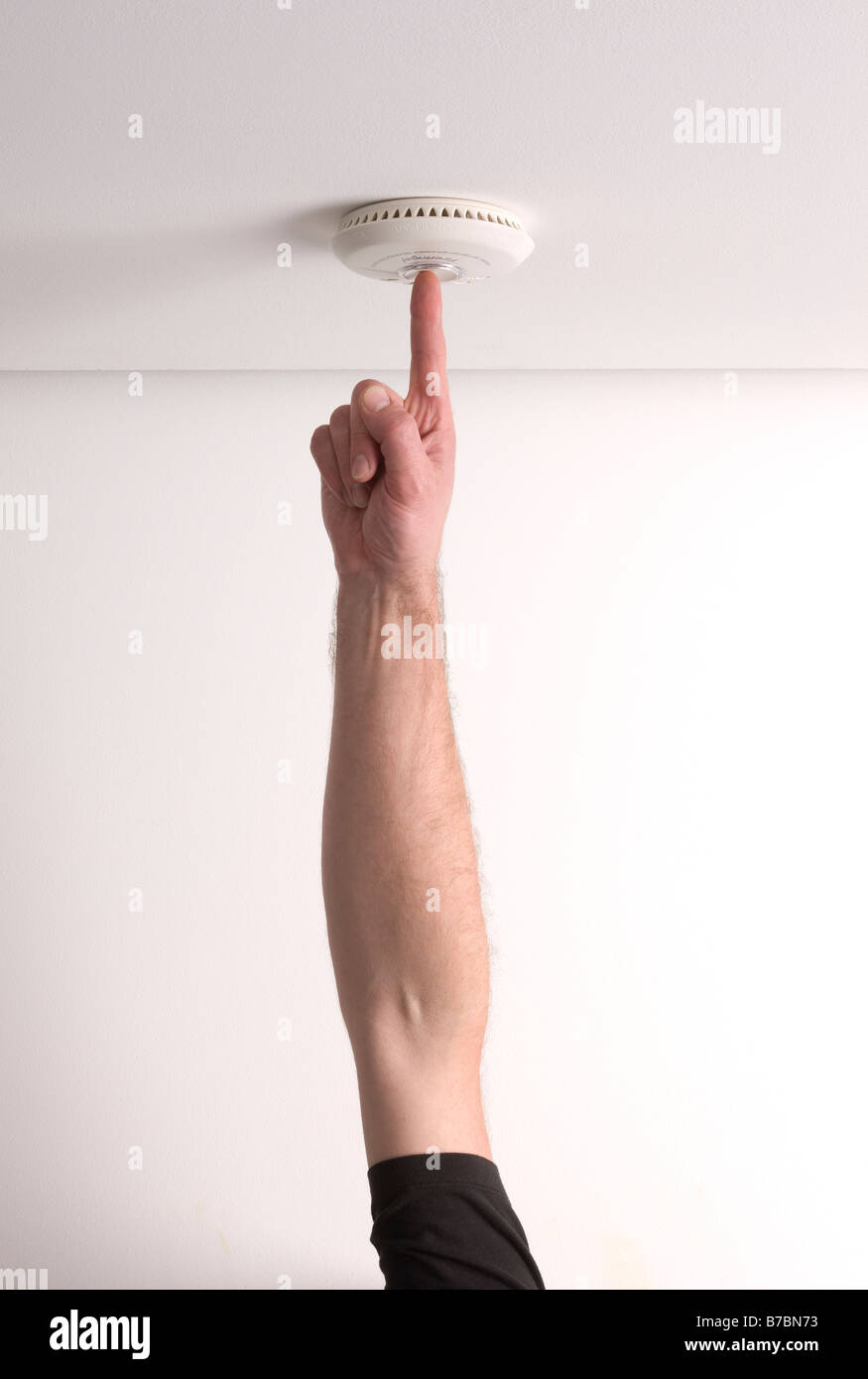 Man testing a domestic fire alarm is working correctly Stock Photo - Alamy