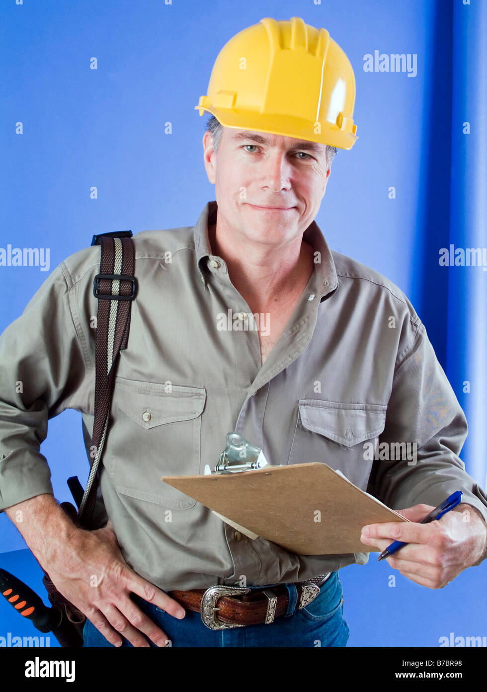 Construction worker with hard hat and clip board standing in front of a ...