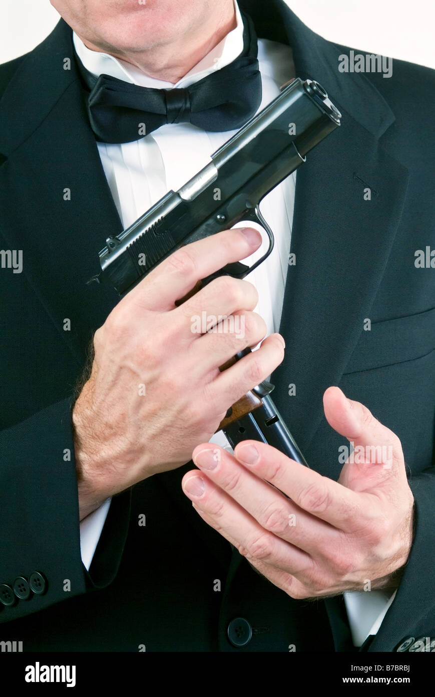 Close up of a man in formal attire loading his automatic weapon taken ...