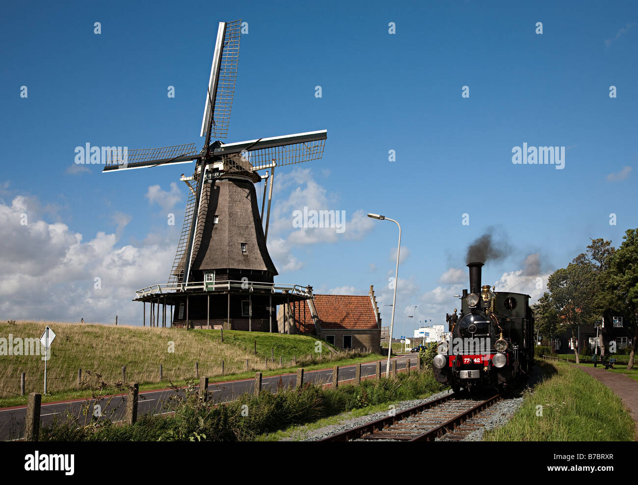 Steam train on tourist railway line with windmill Medemblik Netherlands ...