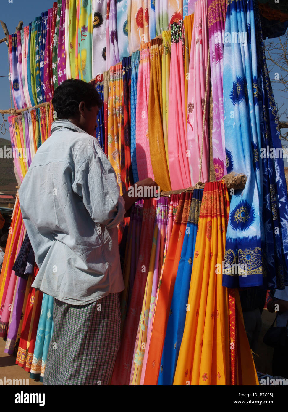 a stall-holder arranges brightly-coloured printed sari lengths in the ...