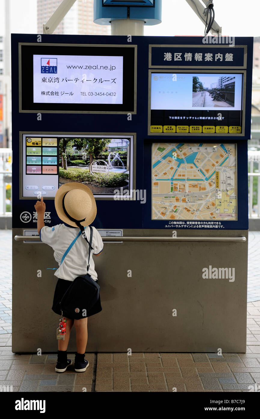 A young schoolboy plays with a touch panel map device outside a station ...