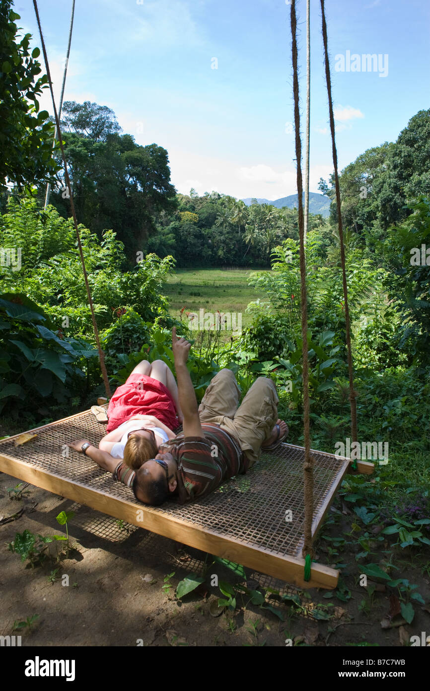 A young couple lying on a giant swing looking up at the sky in the Sri ...