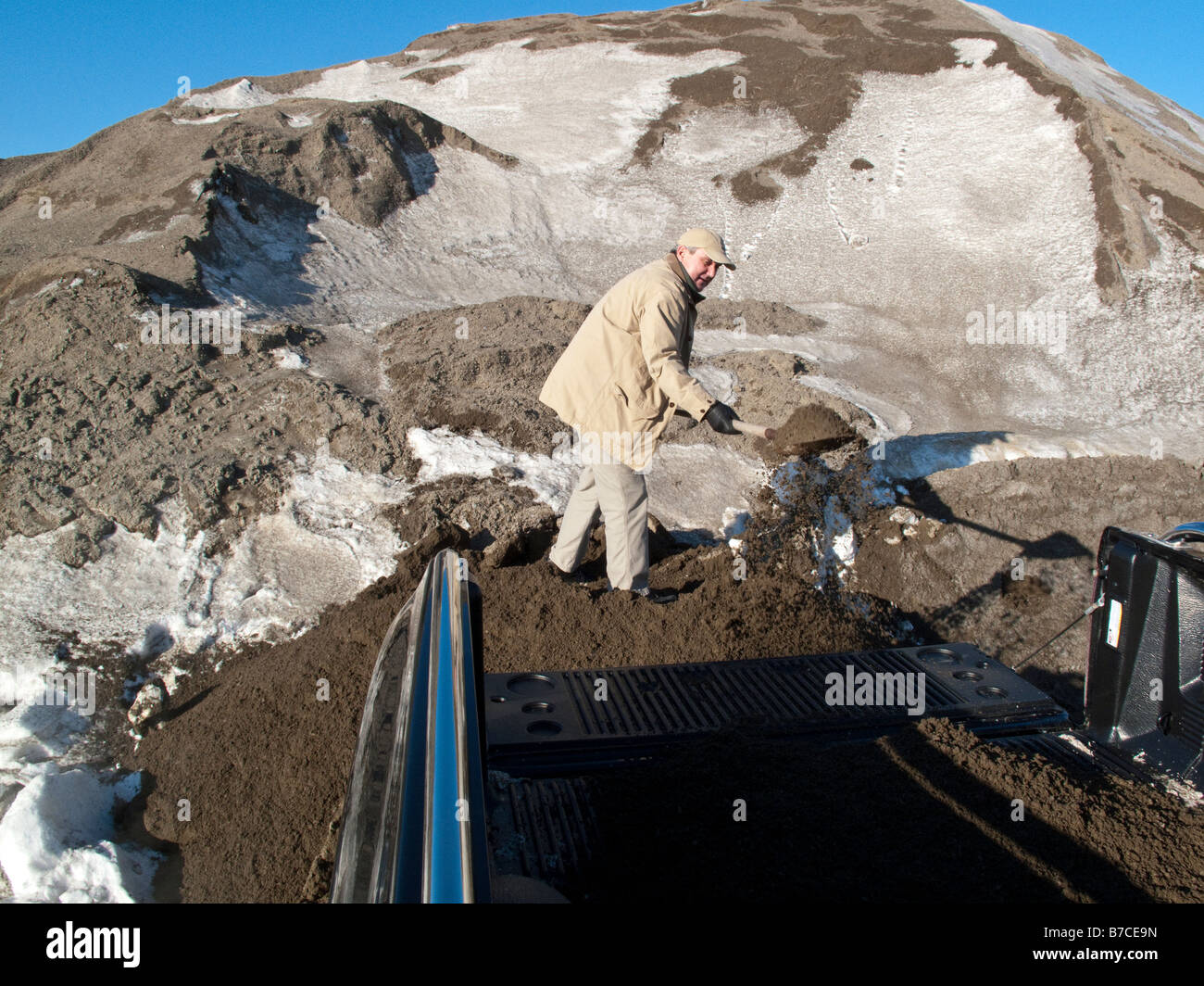 Man shoveling sand for ice filled driveway at transportation garage in ...