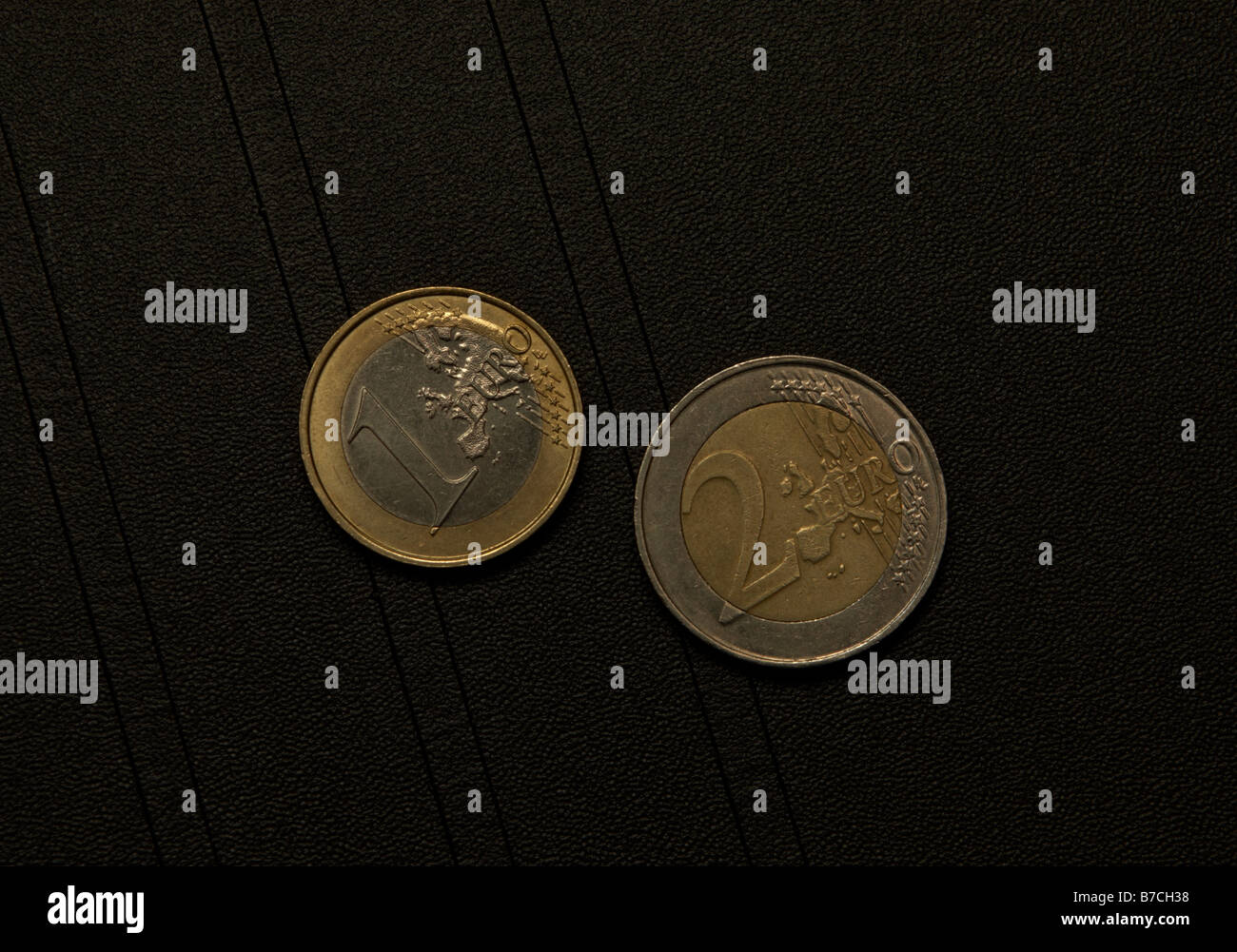 One Euro and two Euro coins next to each other on a black background ...