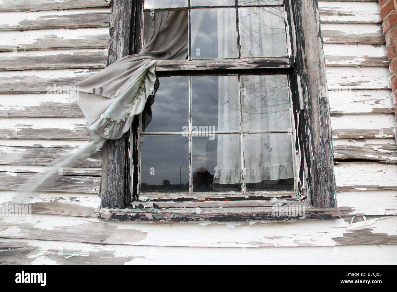 A curtain flutter out the broken window Stock Photo - Alamy
