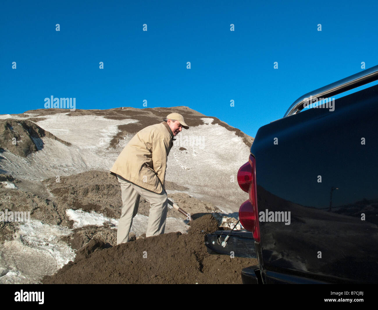Man shovelling sand for ice filled driveway at transportation garage in ...