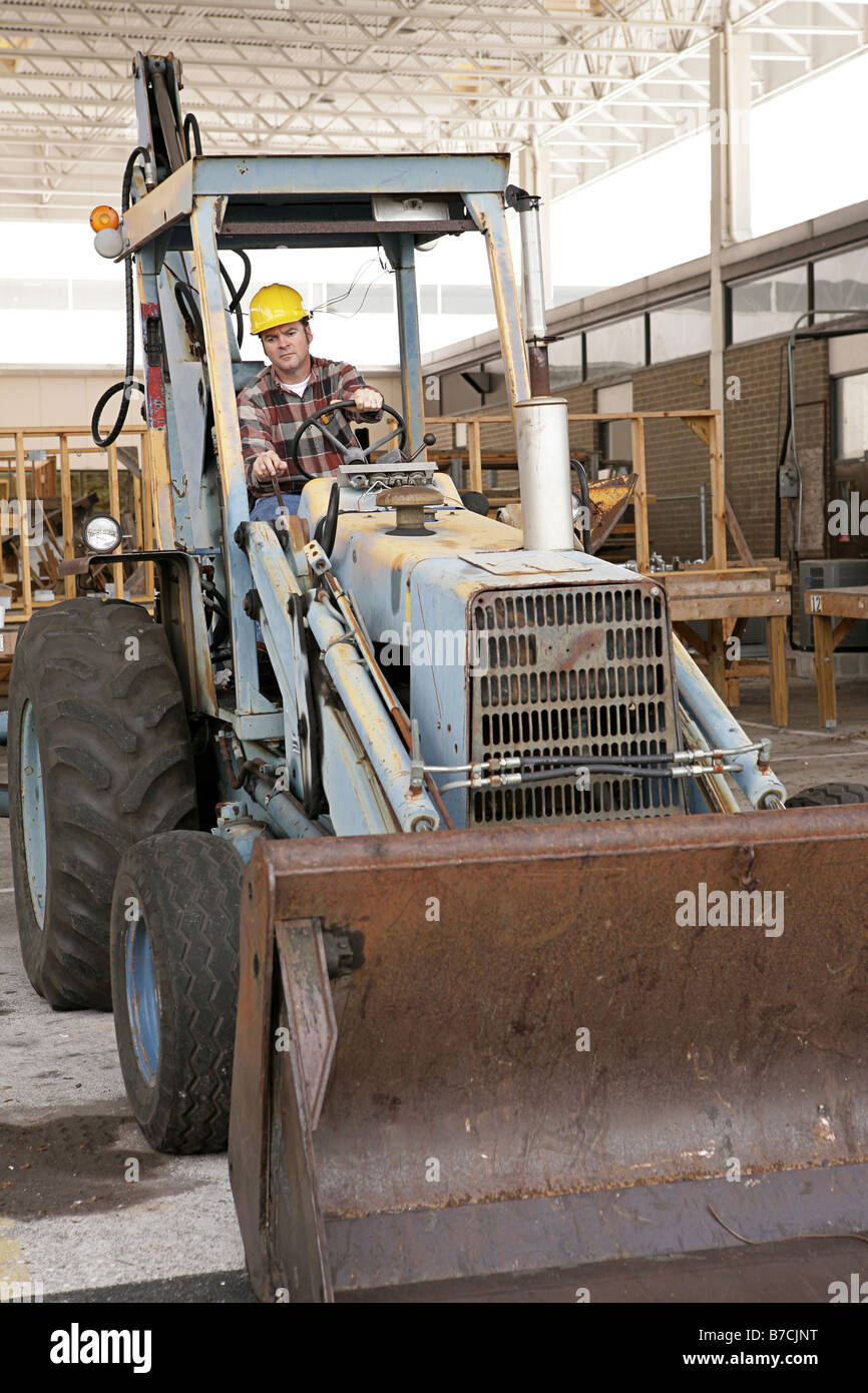 A man on a construction site driving a backhoe loader Stock Photo - Alamy