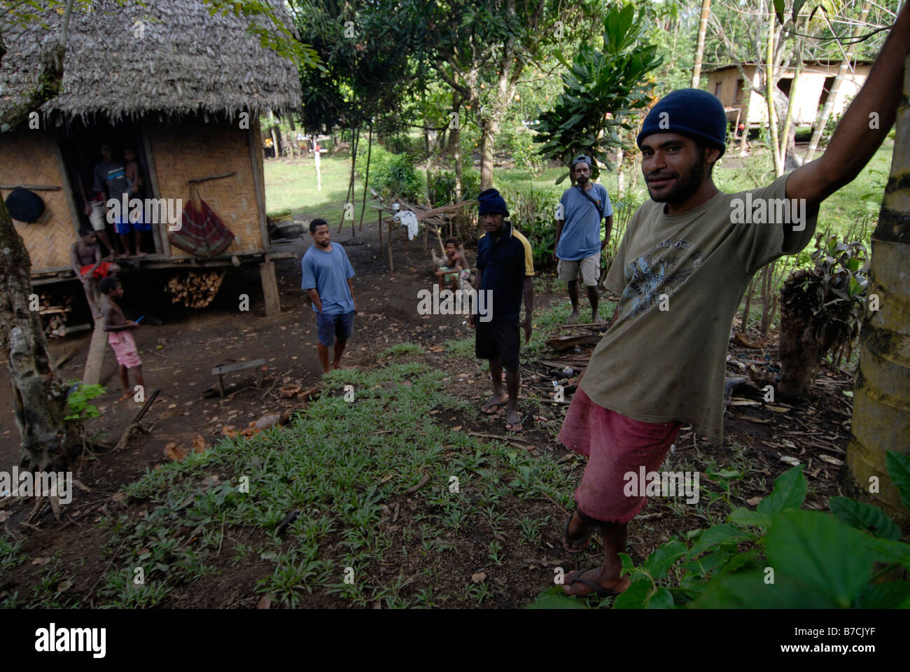 People on the island of Karkar, Papua New Guinea, in front of a typical ...