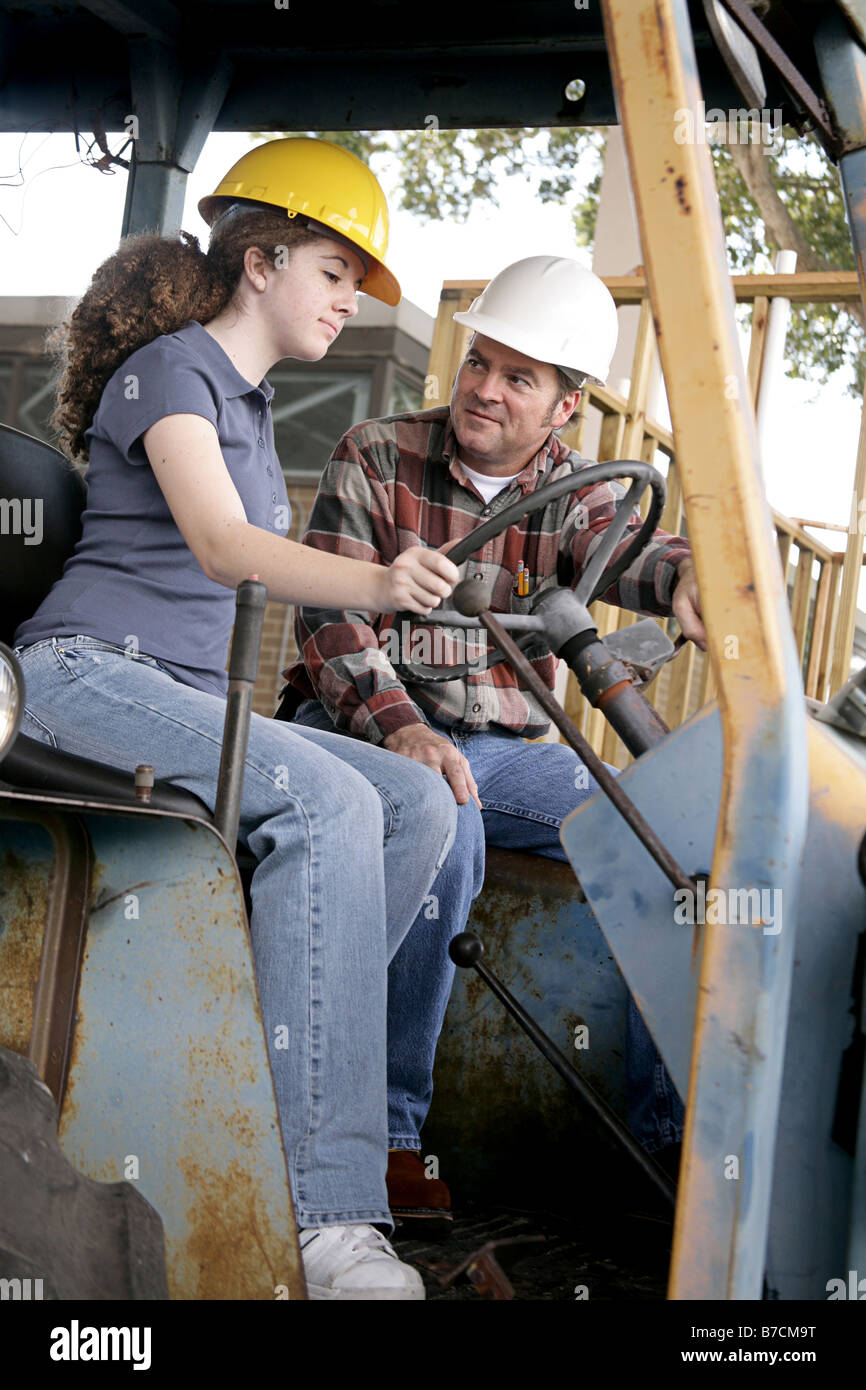 A construction foreman teaching a young worker how to drive heavy ...