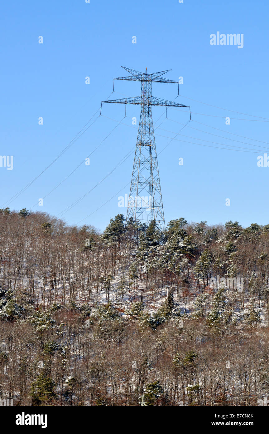 Tower for high tension power lines in winter with snow evergreen trees ...