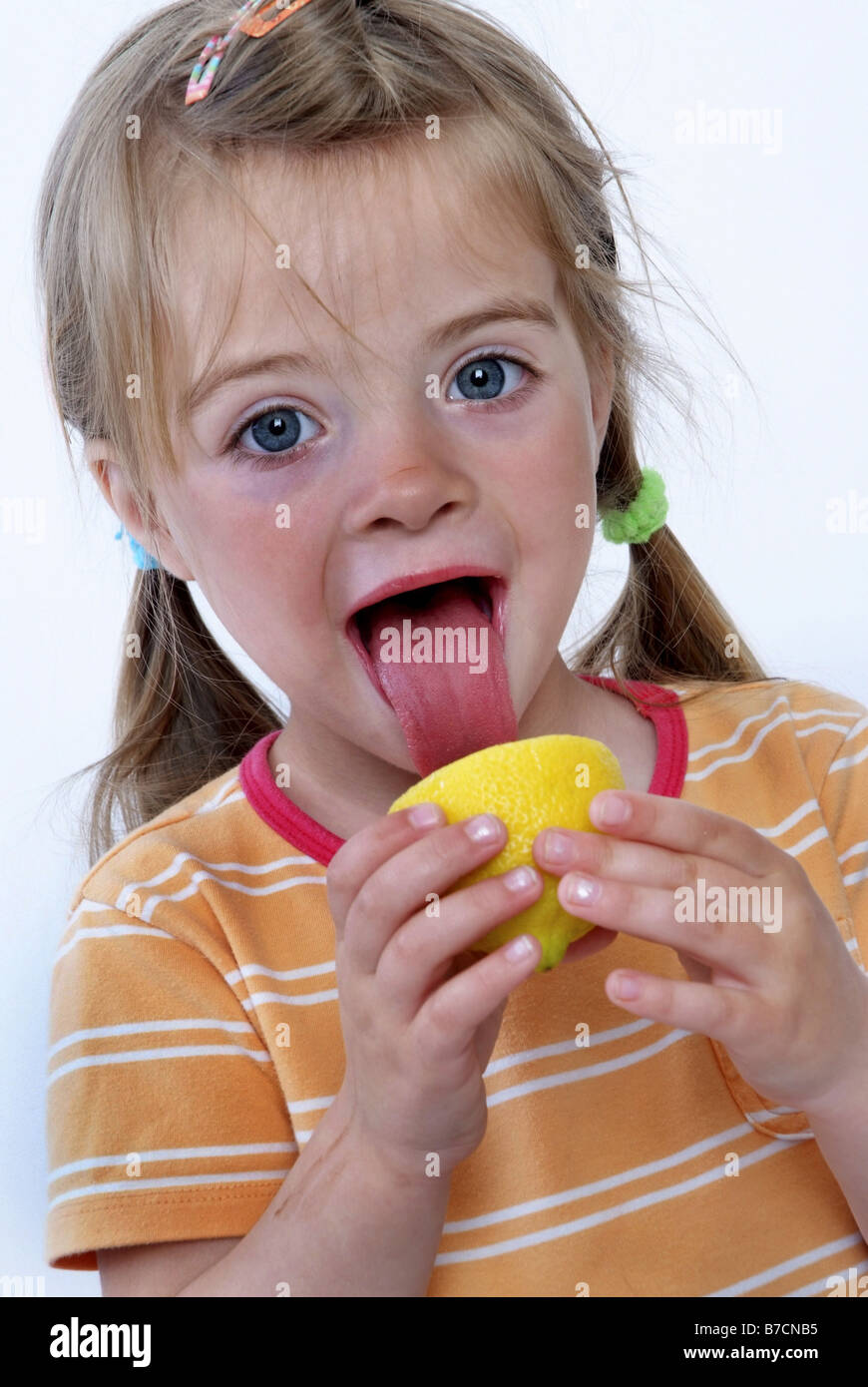 small girl licking at a lemon Stock Photo - Alamy