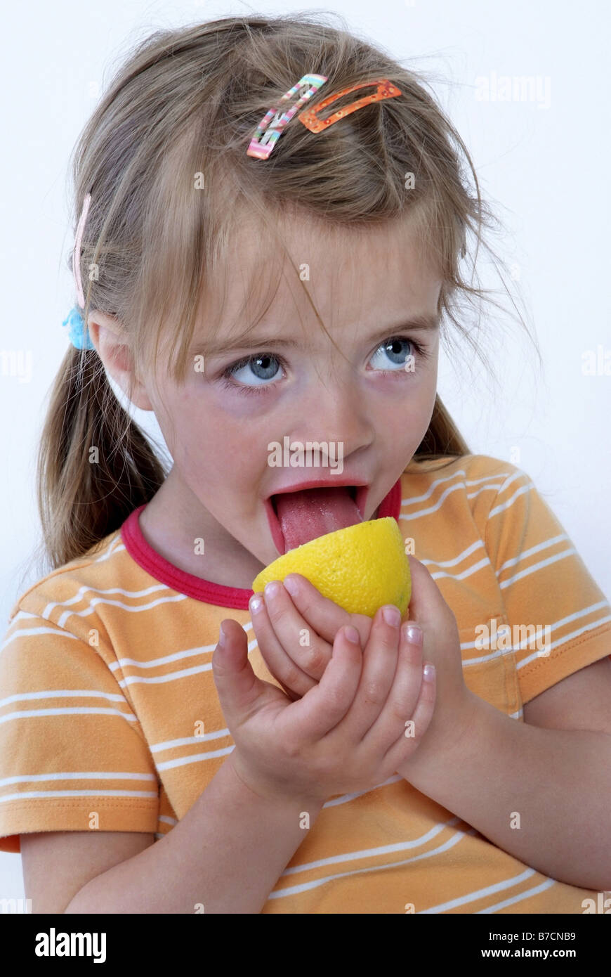 small girl licking at a lemon Stock Photo - Alamy