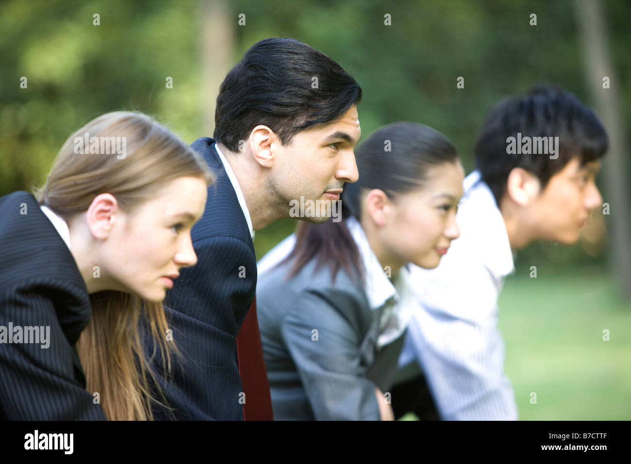 Four business people crouching on the lawn side view Stock Photo - Alamy