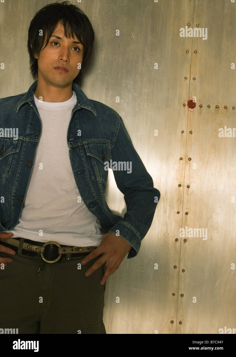 Young man standing by wall Stock Photo - Alamy