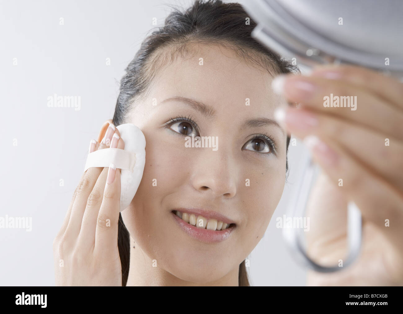 Woman applying powder with puff Stock Photo - Alamy