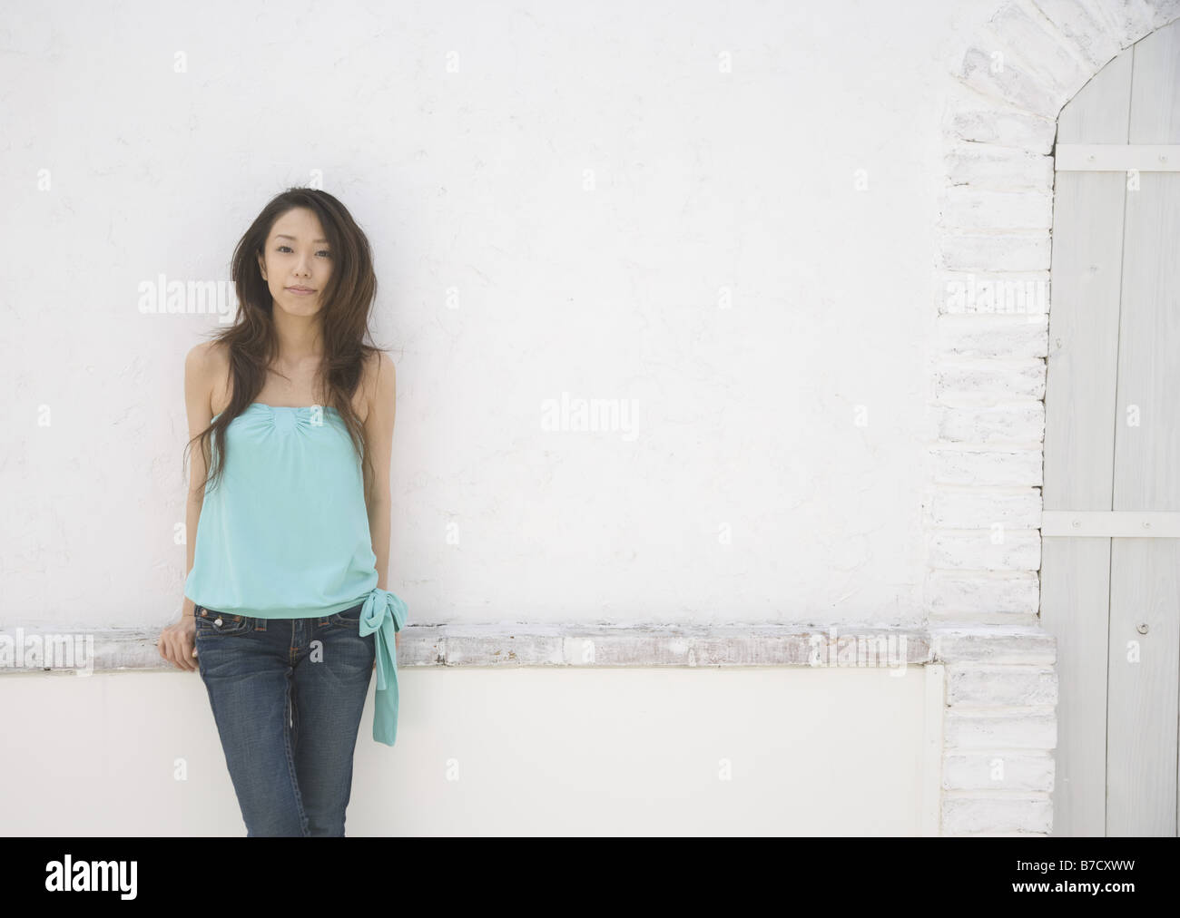 Woman leaning against wall Stock Photo - Alamy