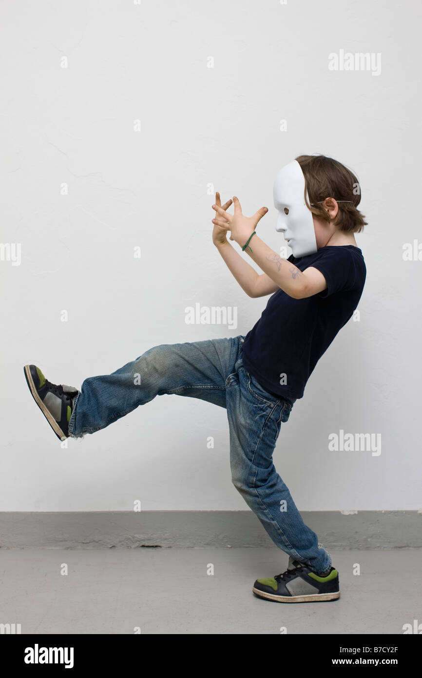 A young boy wearing a mask and standing on one leg, side view Stock ...