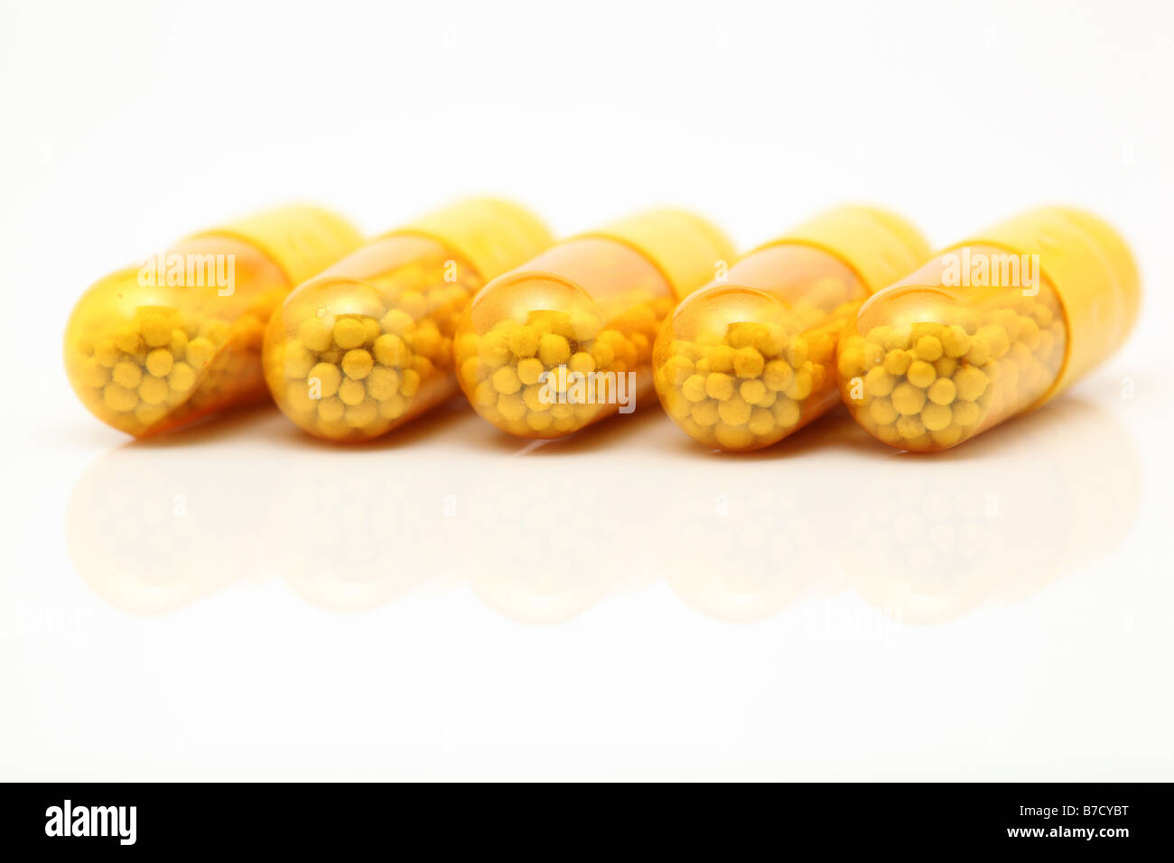 yellow medical capsules closeup detail with reflection on white ...