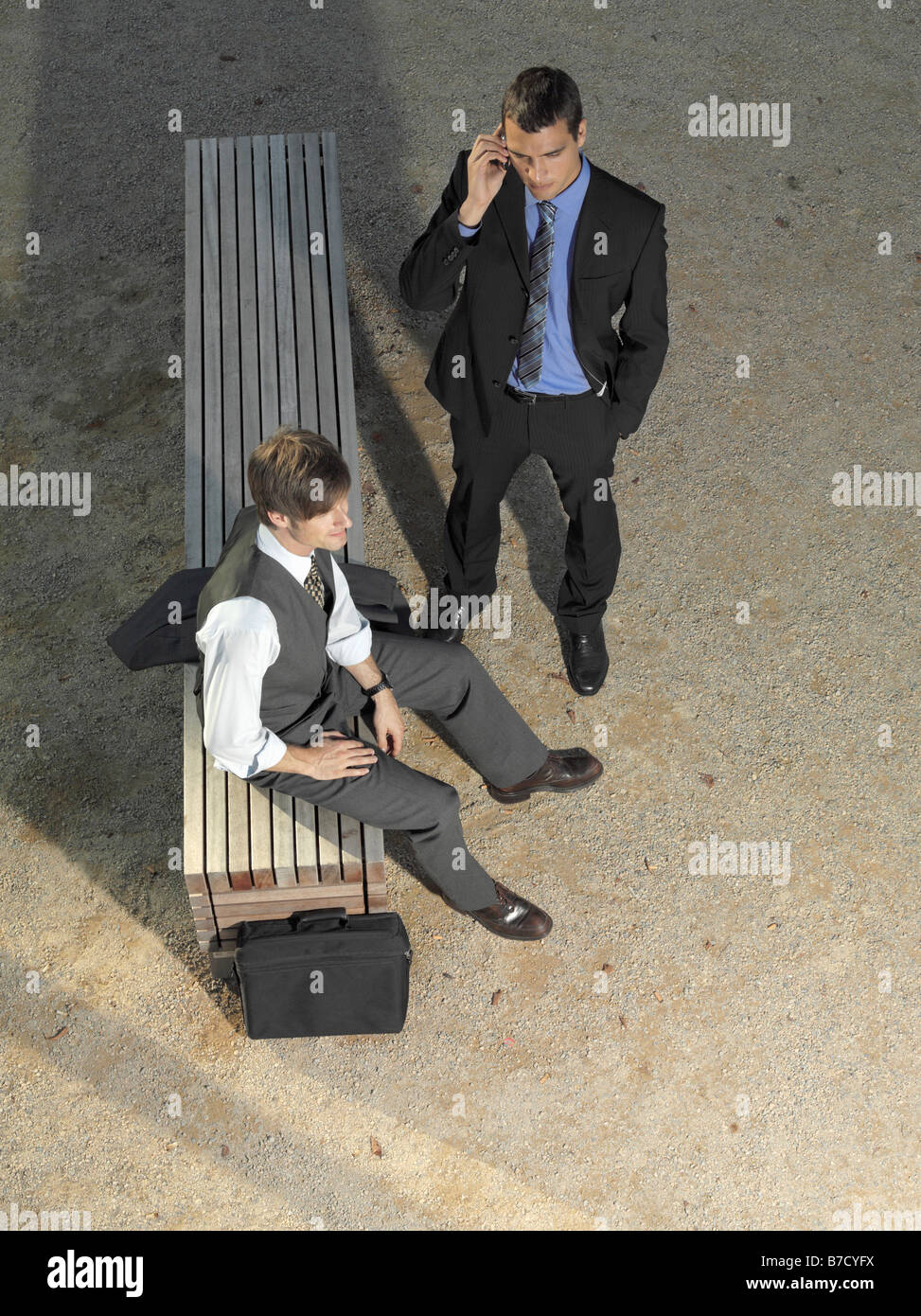 Two businessmen waiting by a bench Stock Photo - Alamy