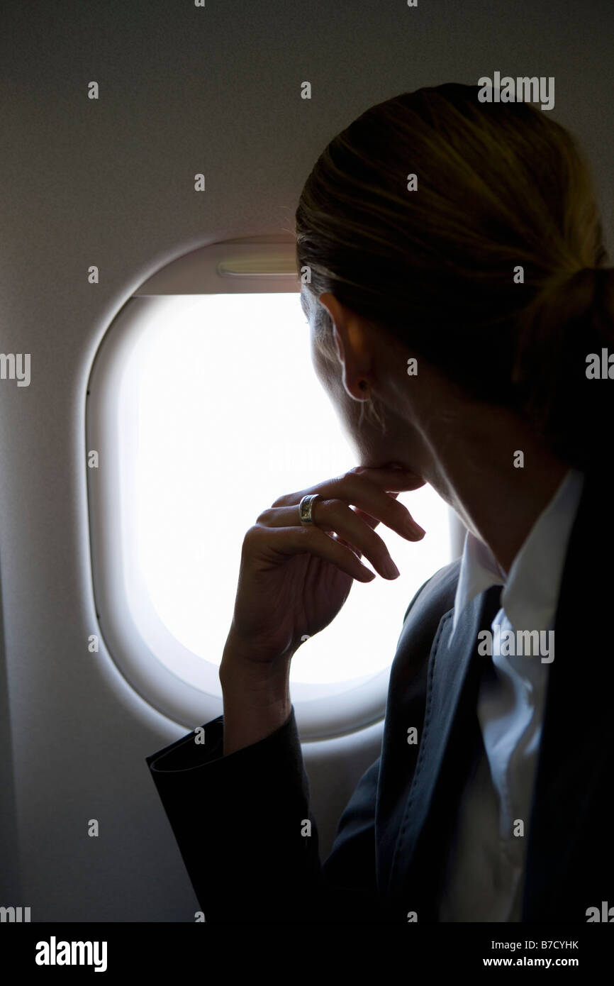 A female passenger looking through a window on a plane Stock Photo - Alamy