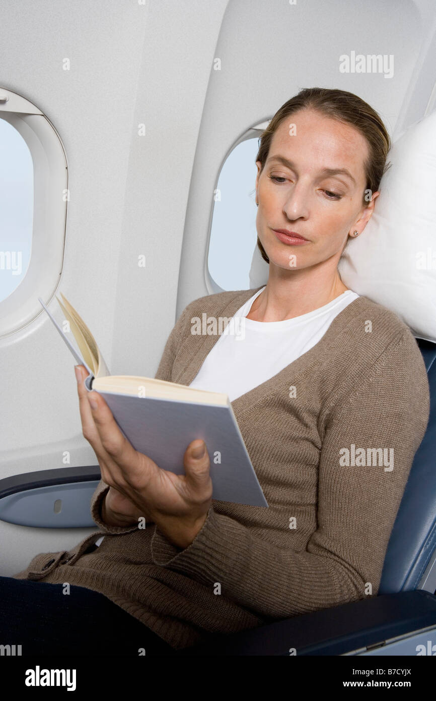 A female passenger reading on a plane Stock Photo - Alamy