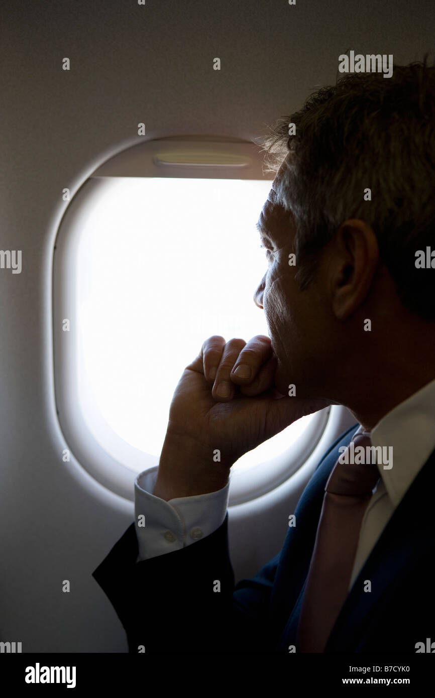 A male passenger looking through a window on a plane Stock Photo - Alamy