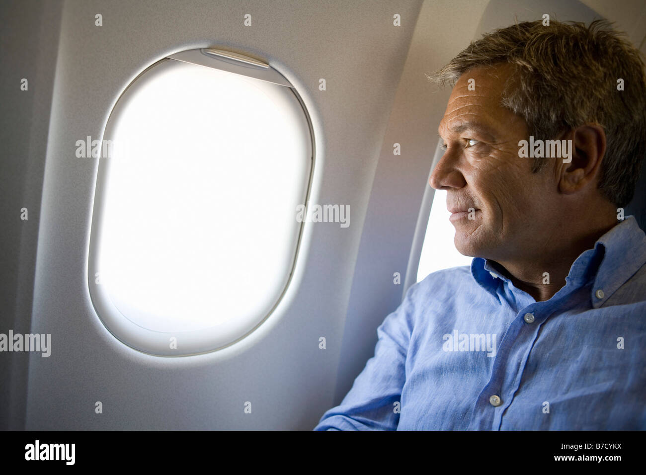 A male passenger on a plane looking through window Stock Photo - Alamy