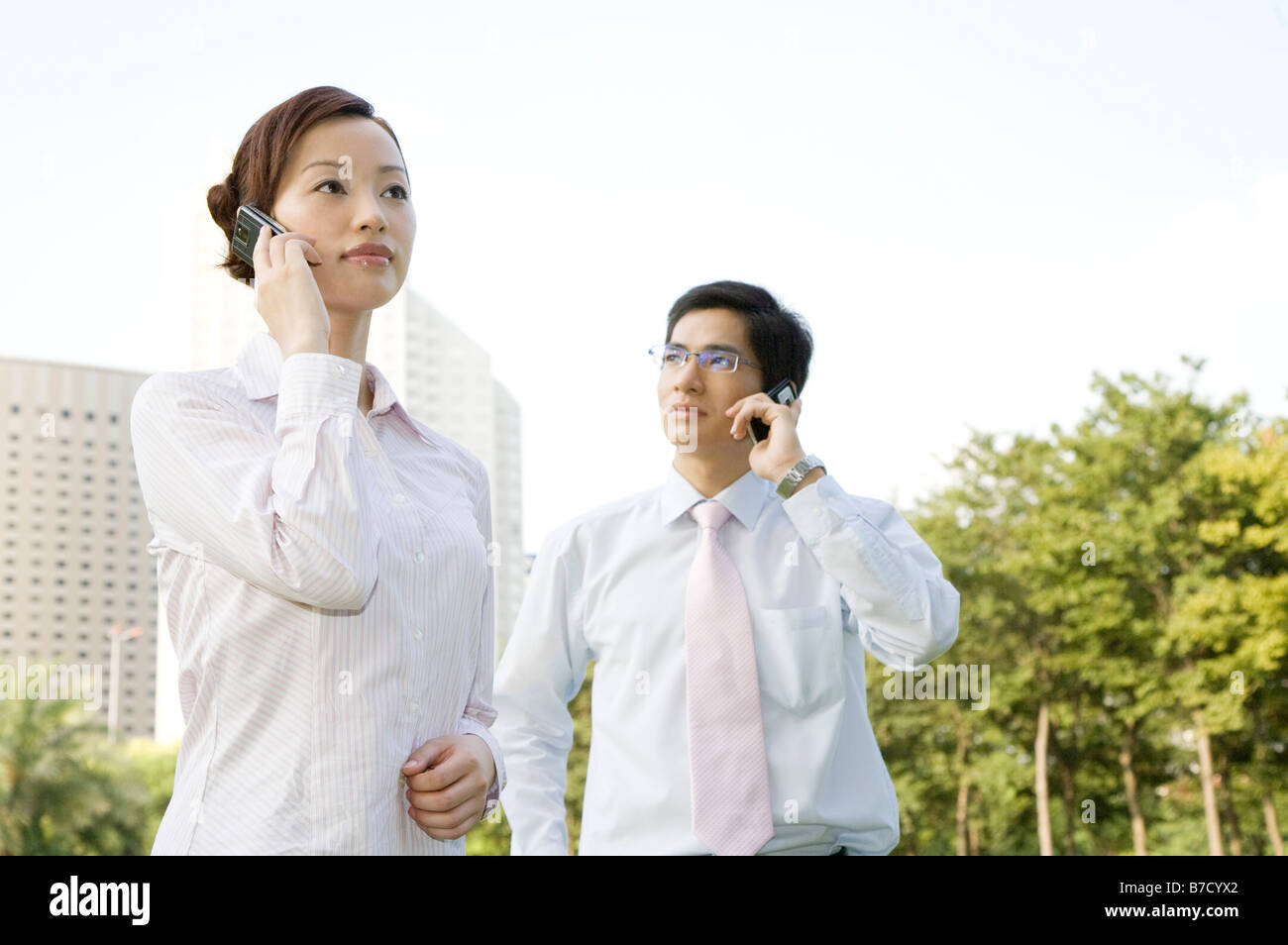 Two business people talking on mobile phone Stock Photo - Alamy