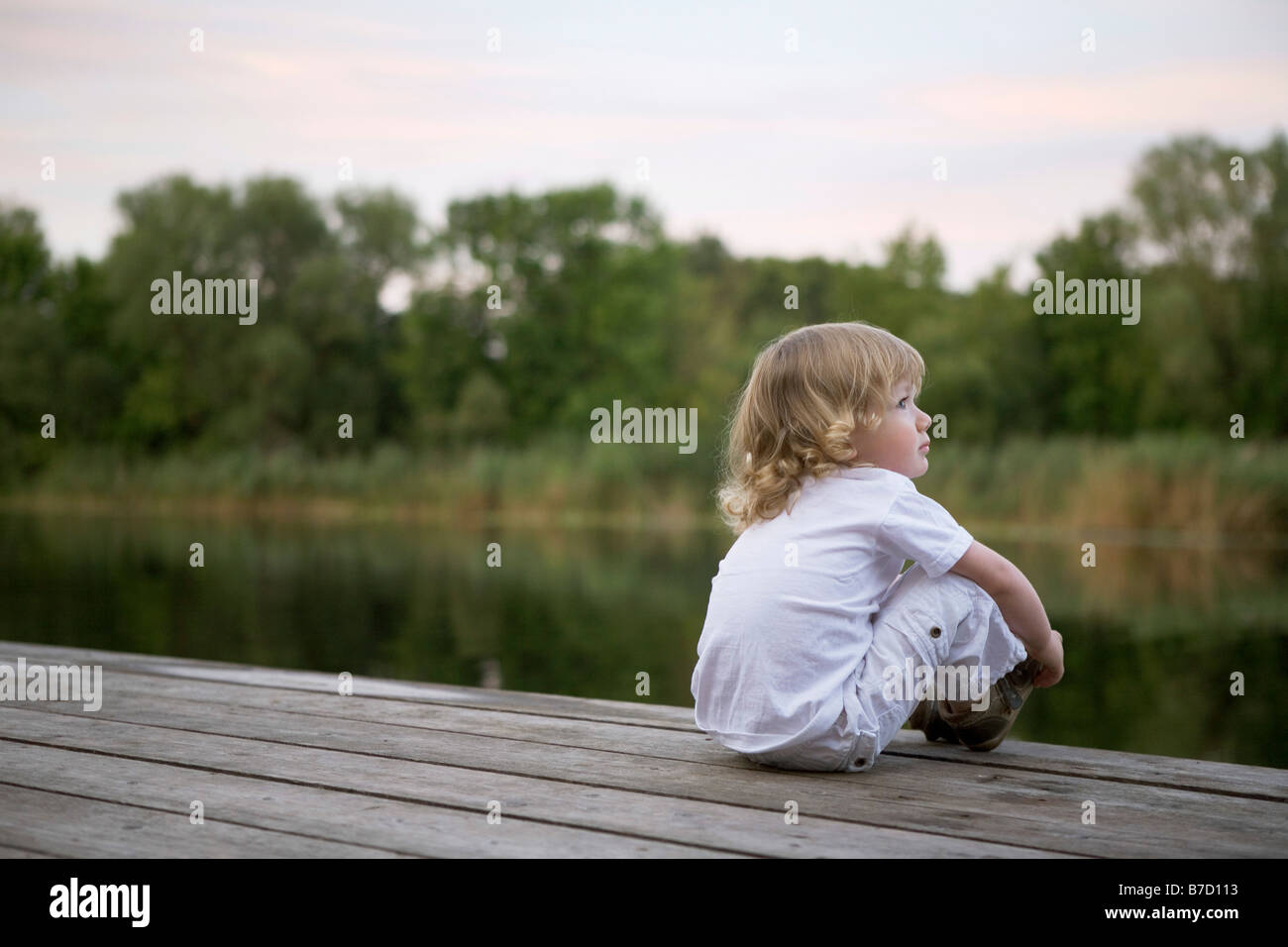 A boy sitting on a jetty Stock Photo - Alamy