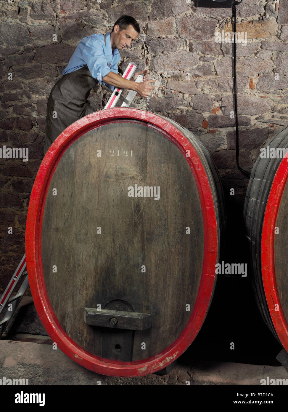 A vintner using a glass wine thief to get a sample from a barrel Stock ...