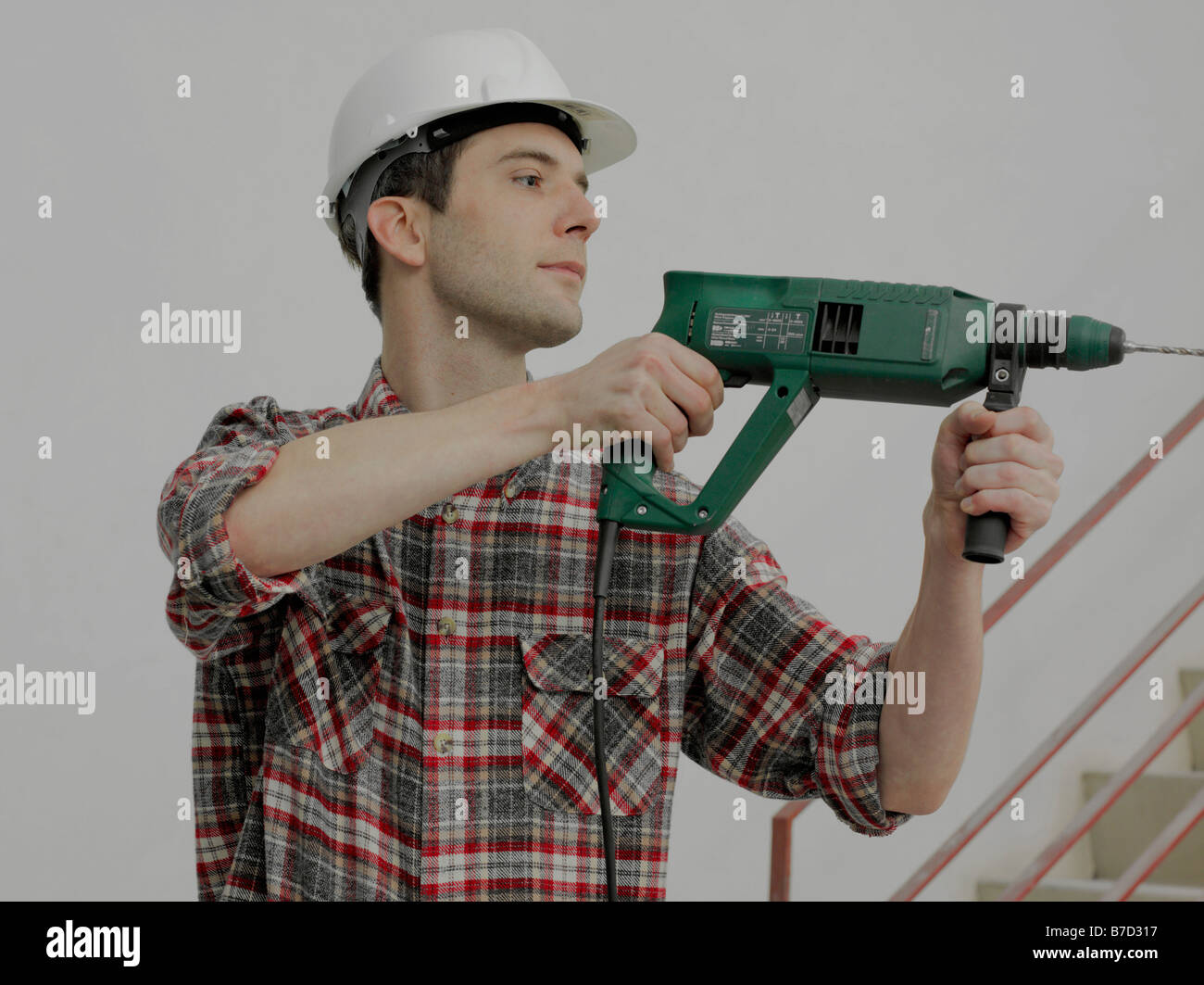 A construction worker using a drill on a wall Stock Photo - Alamy