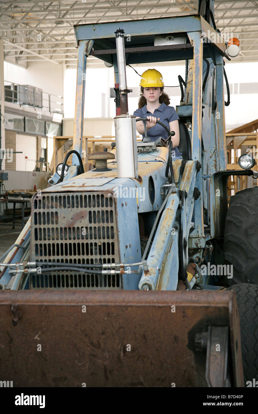 A female construction worker driving an earth mover on a construction ...