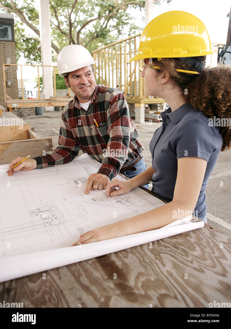 A construction foreman teaching a female apprentice how to read ...