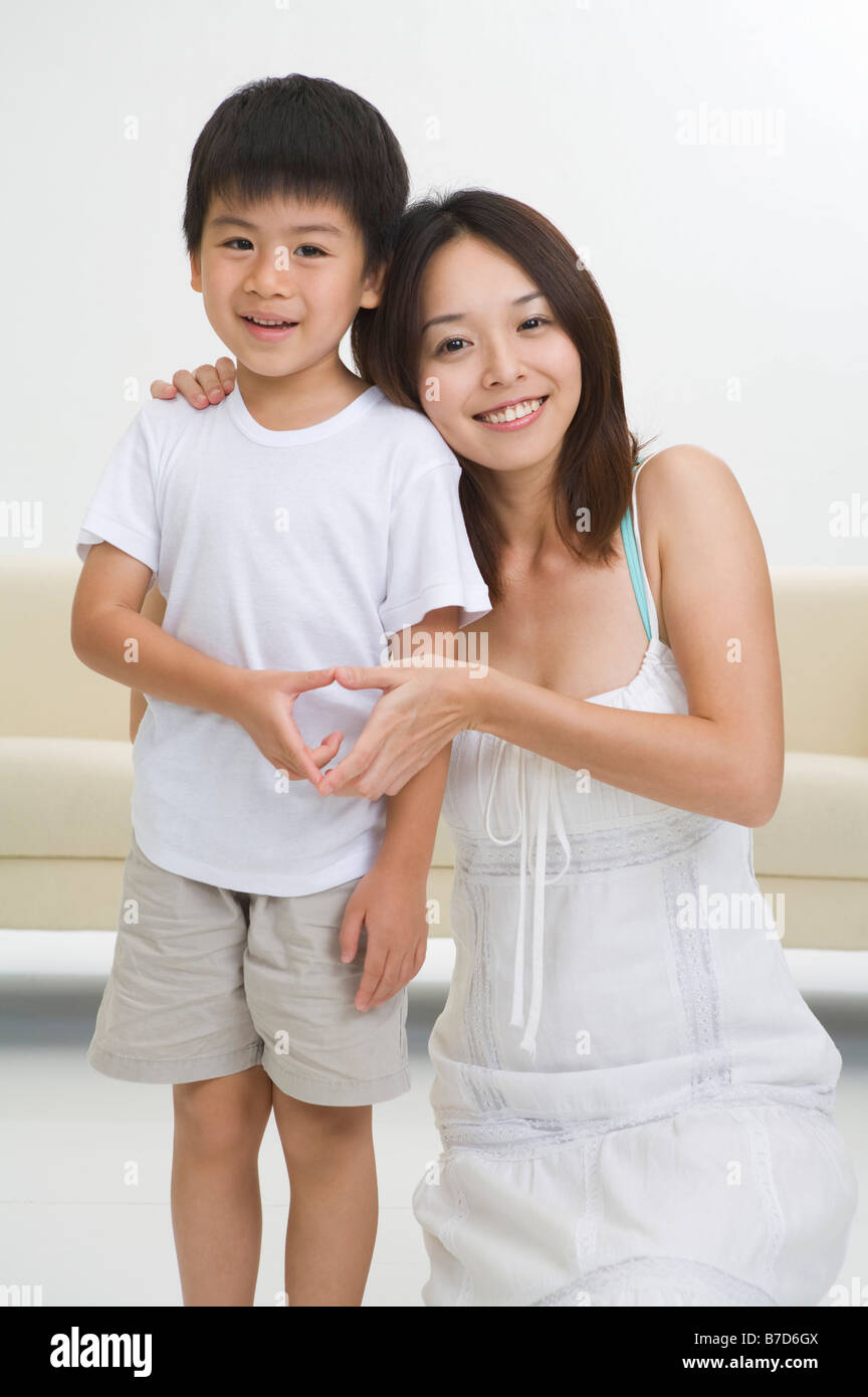 Young mother with one child making heart shape with fingers and bonding ...