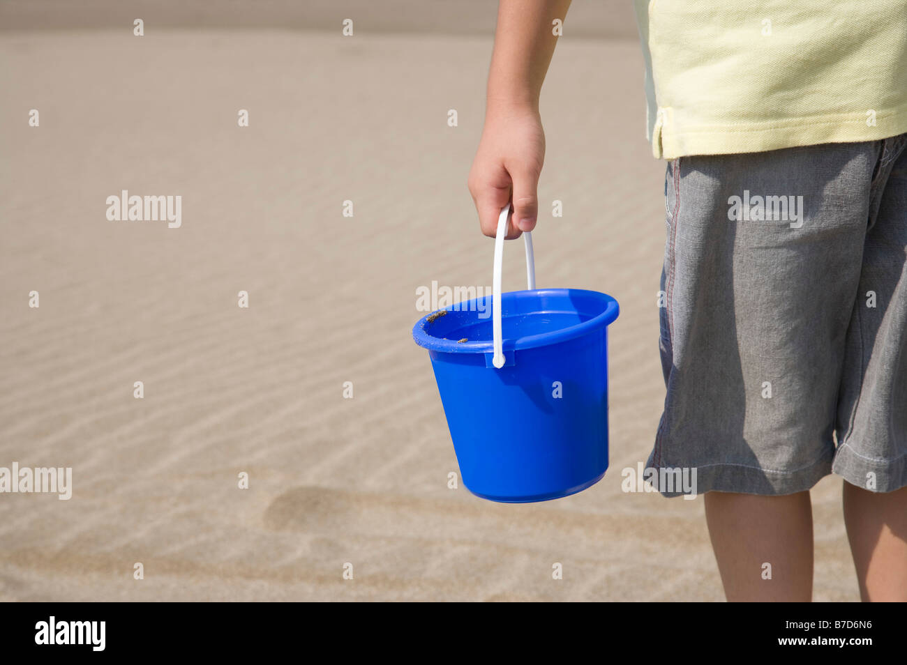 Little boy carrying a small blue bucket Stock Photo - Alamy