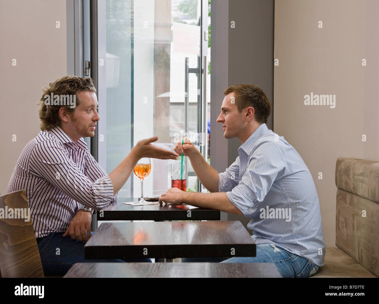 Friends sitting at table talking Stock Photo - Alamy