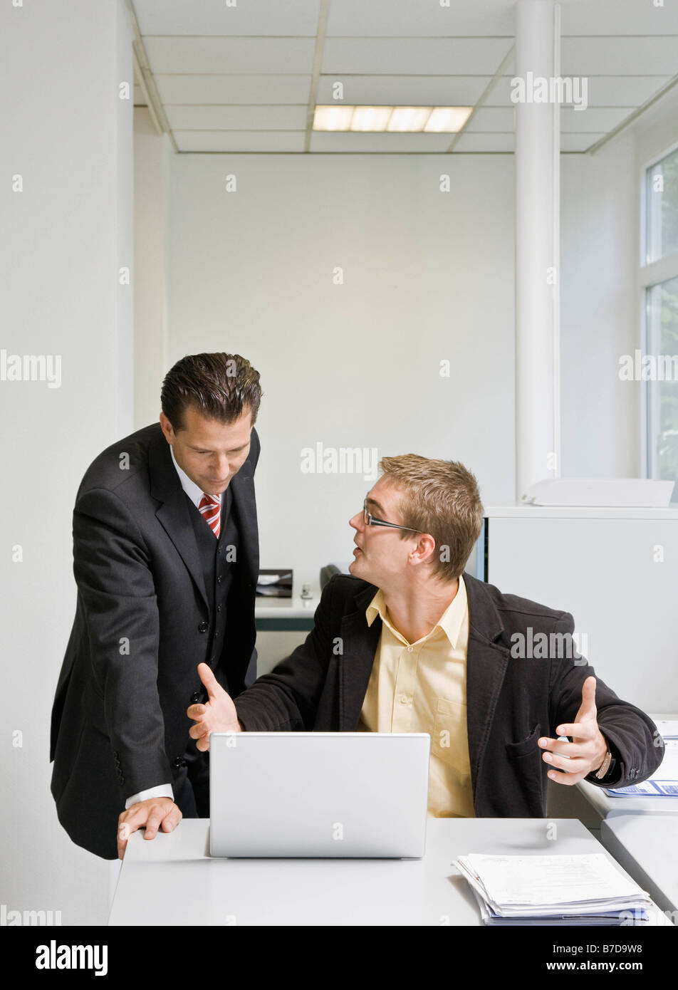 Boss looking at laptop with co-worker Stock Photo - Alamy