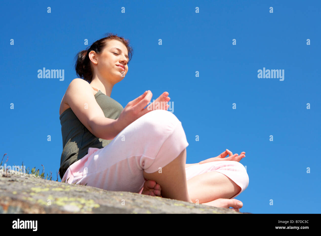 Teenage girl meditating on rock eyes closed Stock Photo - Alamy